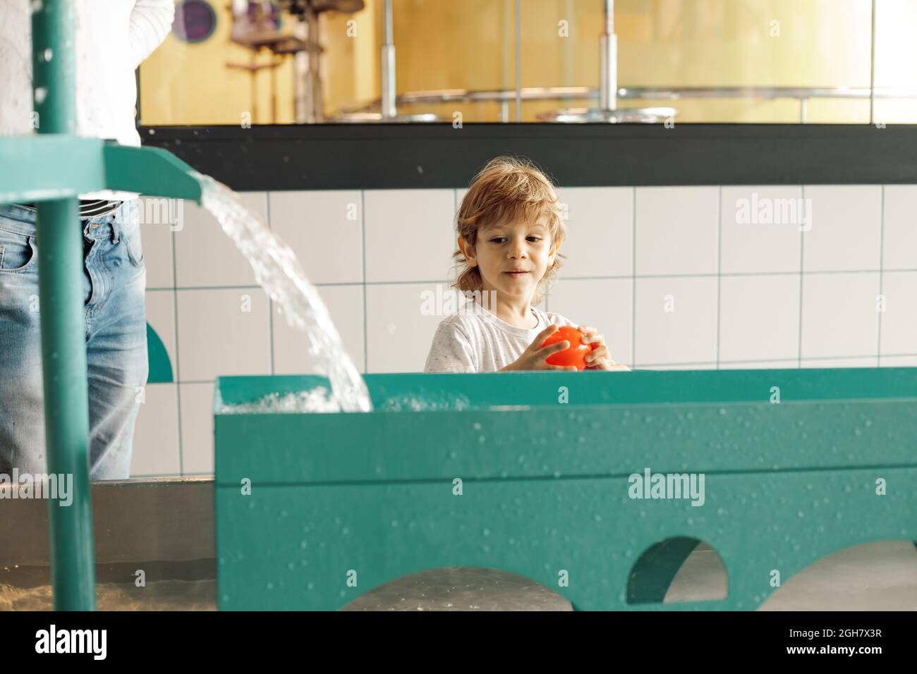 Boy plays on water equipment in entertainment center under supervision ...
