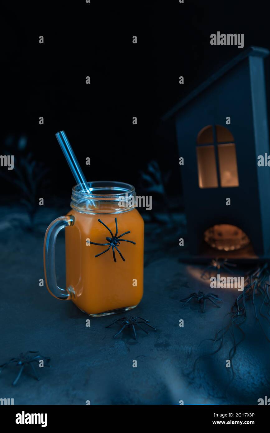 Halloween still life scene with pumpkin mocktail, spiders, spooky black ...