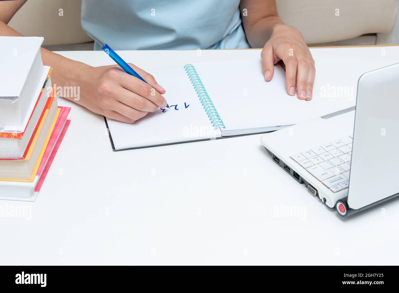 Female student hand holding a pen, writing in a notebook the assignment ...