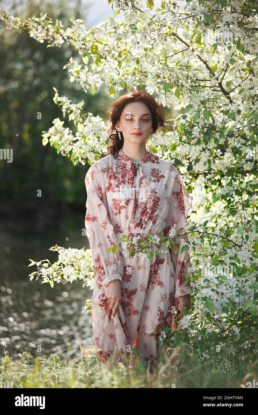 Beautiful romantic woman stands in branches of blooming apple tree ...