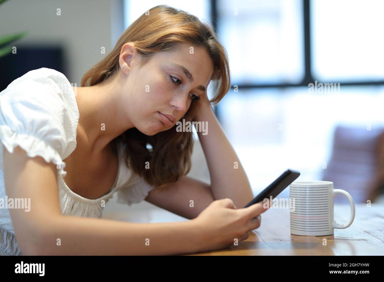 Frustrated and bored woman using smart phone checking content sitting ...