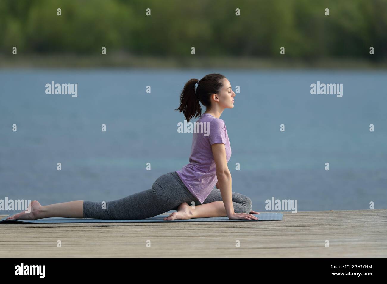 Side view full body portrait of a woman doing yoga pose in a lagoon ...