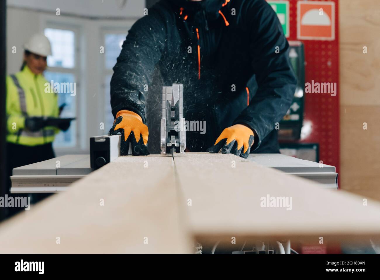 Midsection of male worker using table saw for cutting wooden plank at ...