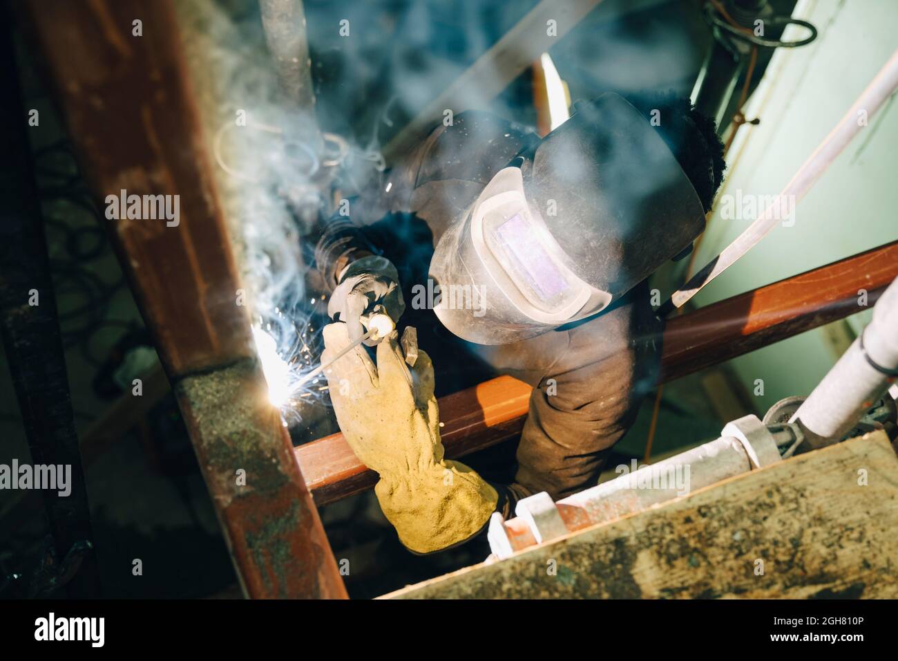 Young worker using welding torch while working at site Stock Photo - Alamy