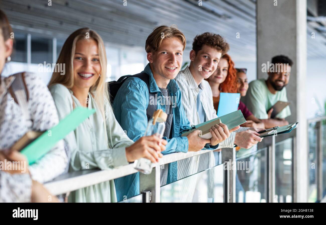 University students standing and looking at camera indoors, back to ...