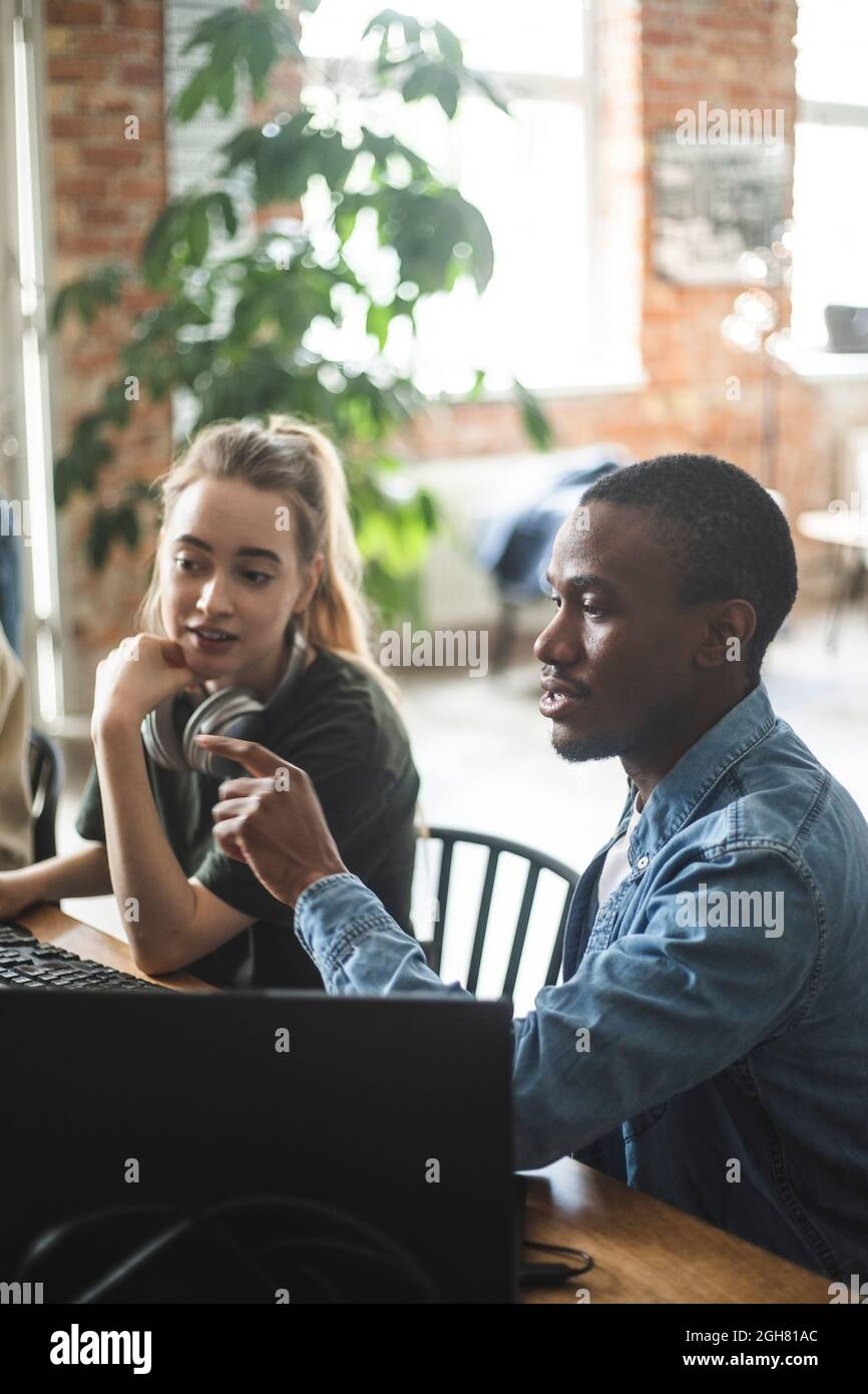 Male programmer explaining female colleague while working at office ...