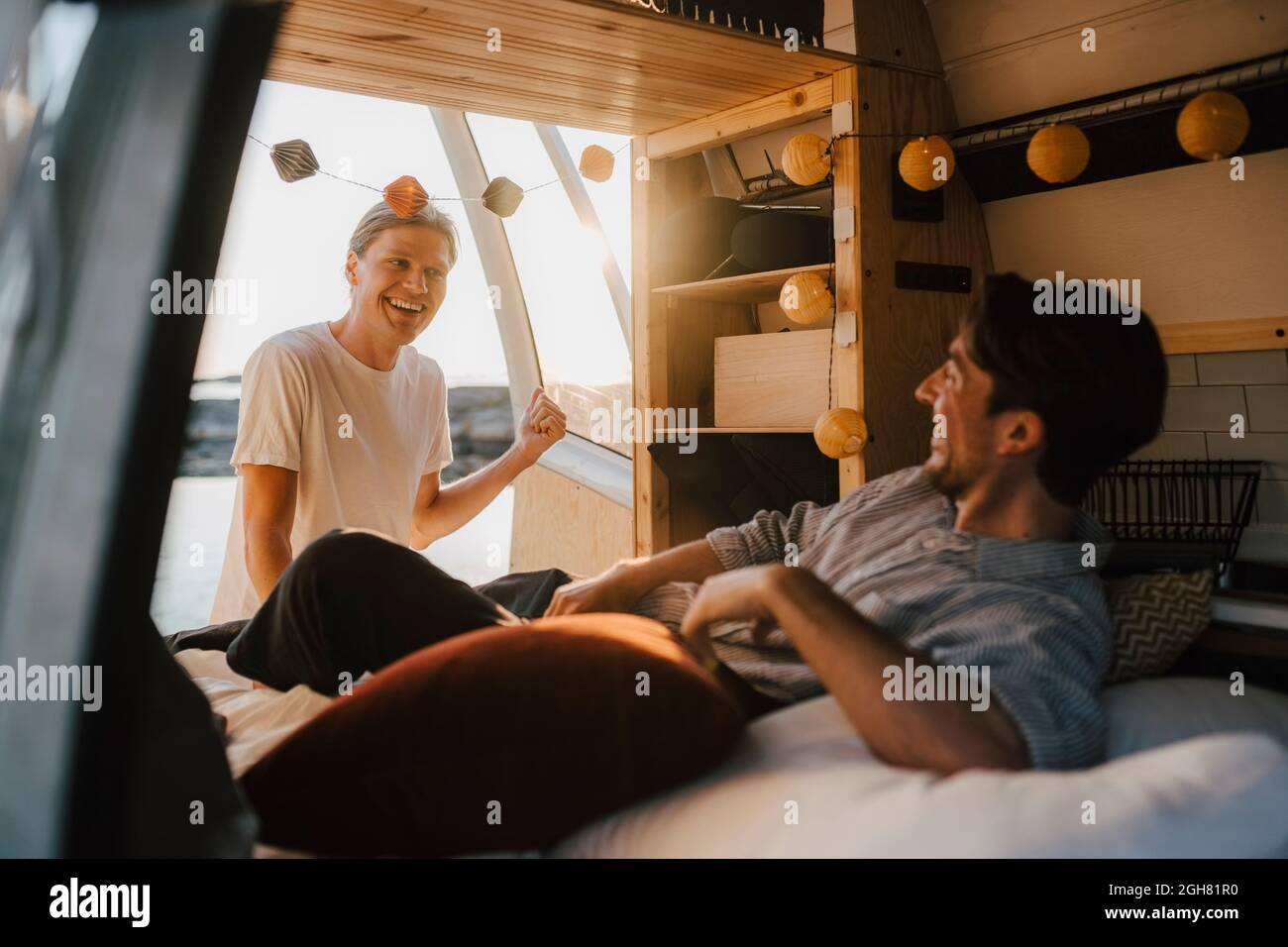 Happy male friends talking with each other in camping van Stock Photo ...