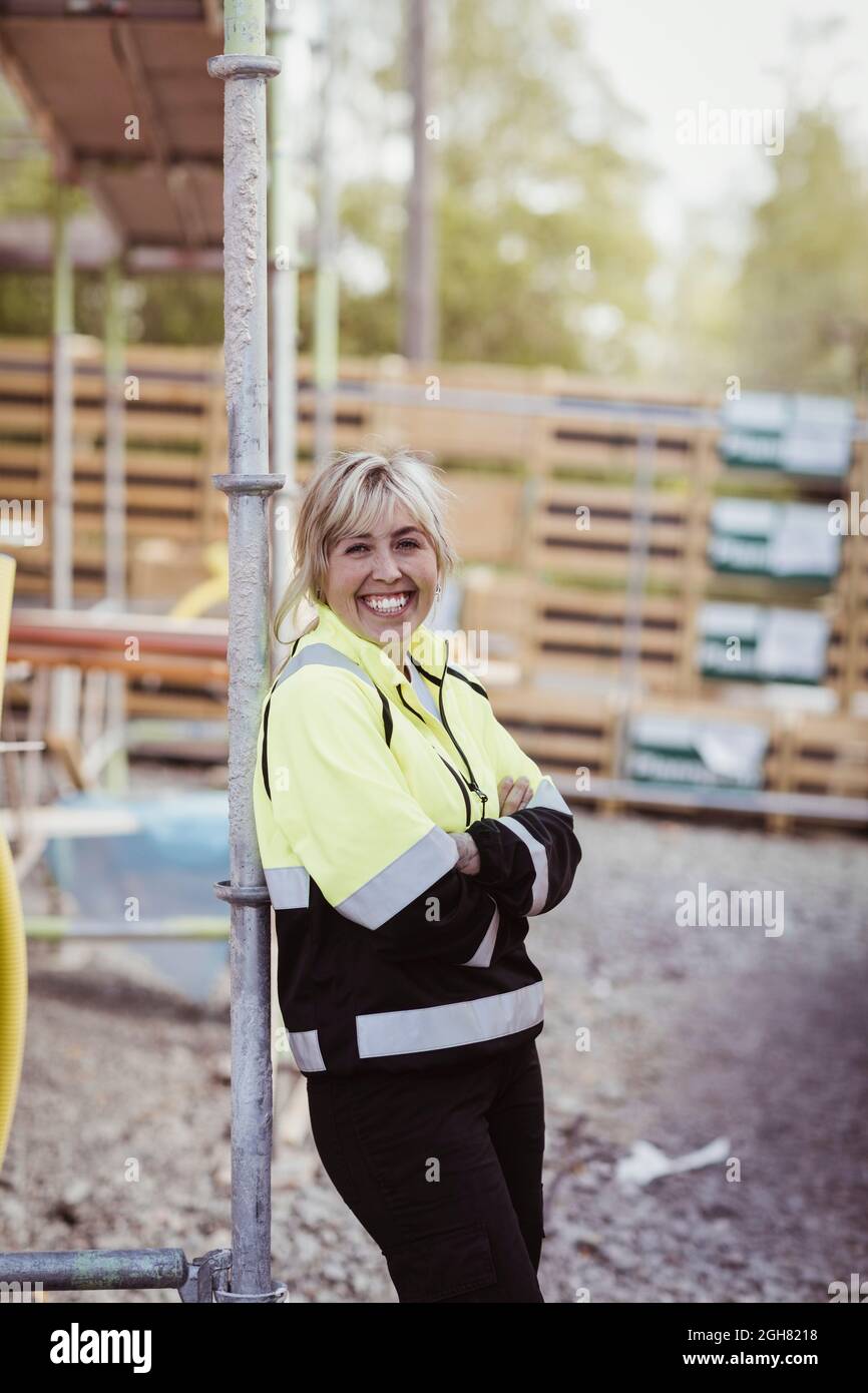 Portrait of happy female building contractor standing with arms crossed ...