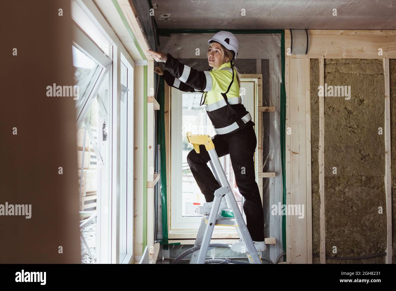 Full length of female building contractor measuring window frame ...