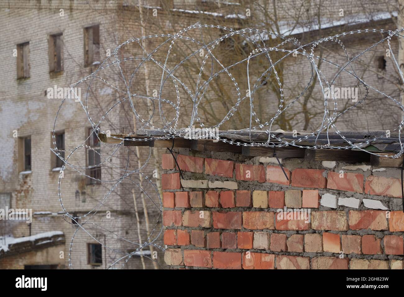 new barbed wire on the roof of an old building near a ravaged area ...