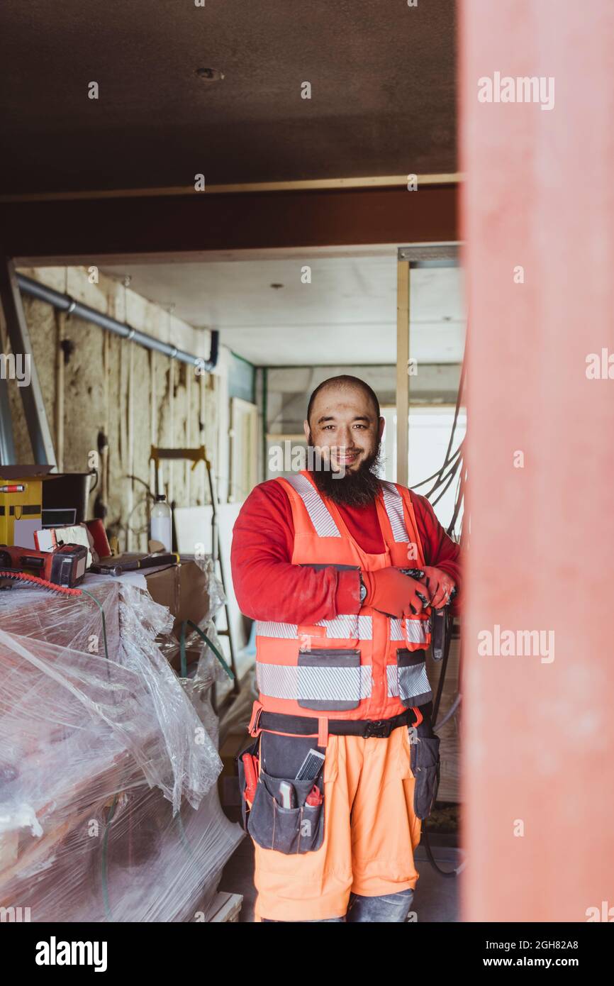 Smiling bearded construction worker working at site Stock Photo - Alamy