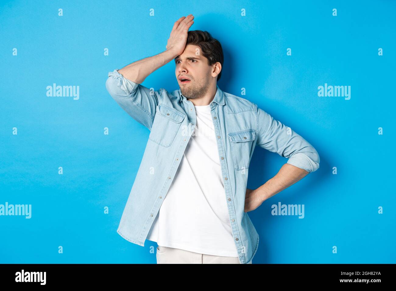 Upset man making facepalm and looking away concerned, forgot something ...