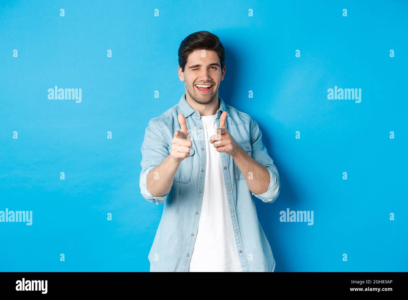 Cheeky handsome guy pointing fingers at you, winking flirty, standing ...