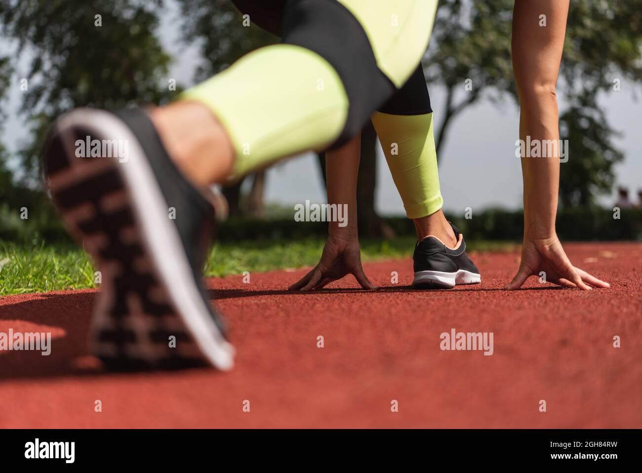 partial view of sportswoman in starting pose on stadium Stock Photo - Alamy