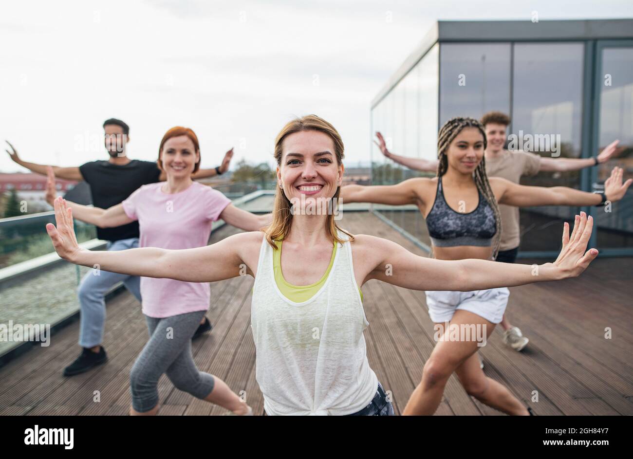 Group of young people doing exercise outdoors on terrace, sport and ...