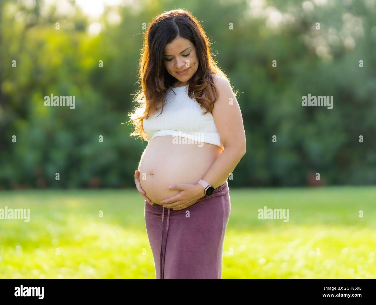Portrait Of A Pregnant Woman Touching Her Abdomen While Looking Down