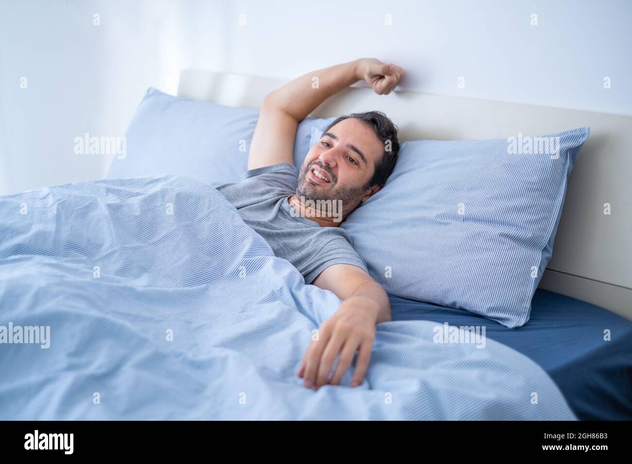One man stretches muscles and waking up from bed Stock Photo - Alamy