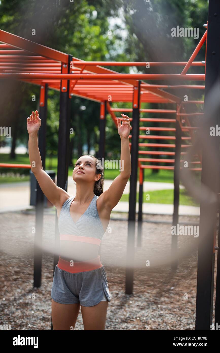 young athletic woman with raised hands preparing for exercise on pull ...