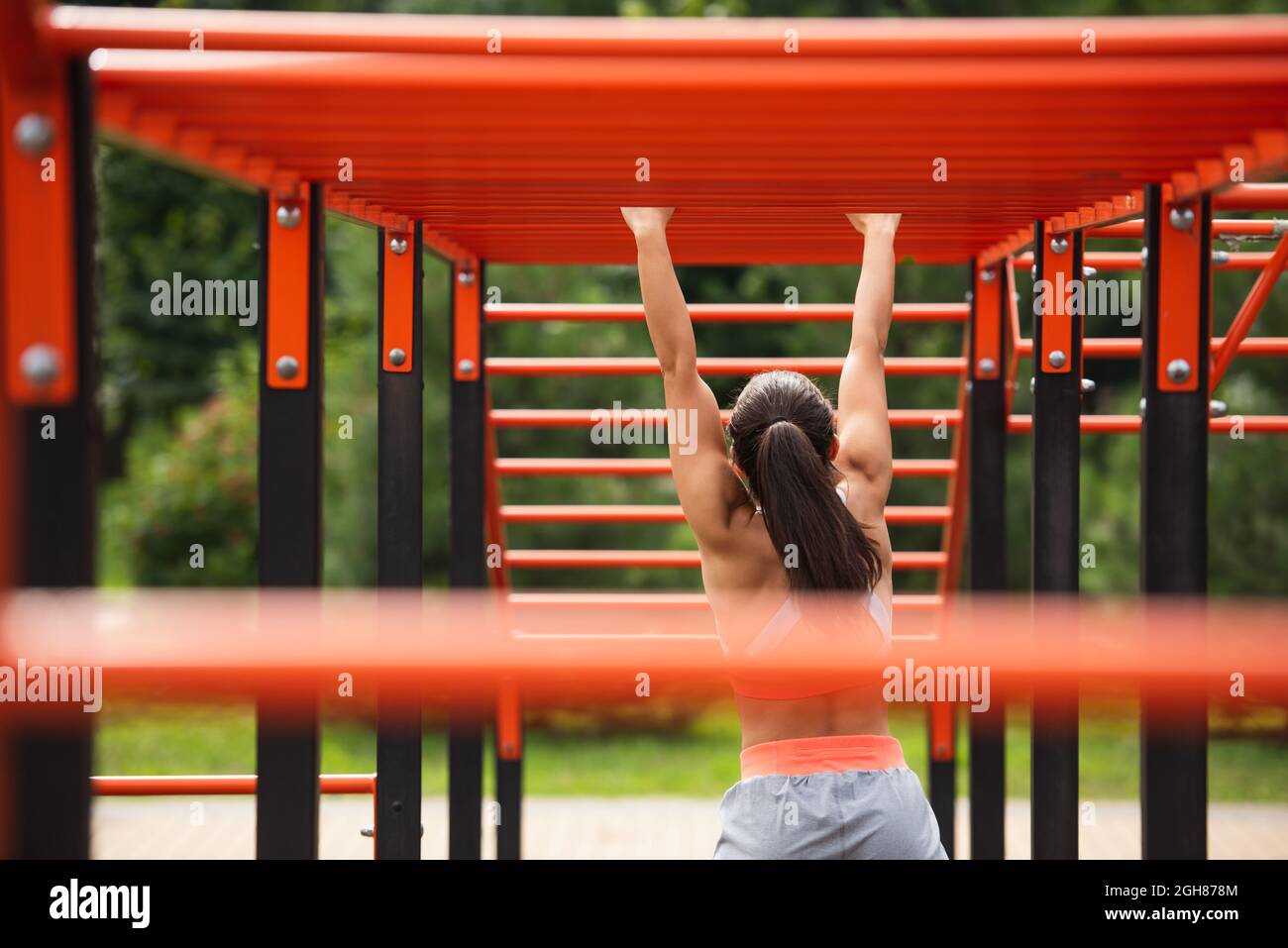back view of athletic woman exercising on orange horizontal ladder ...