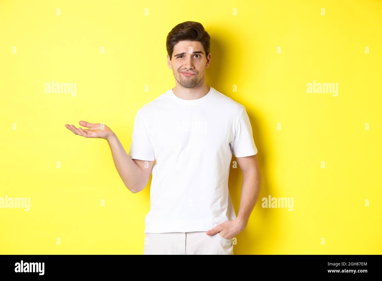 Confused and displeased guy raise hand, grimacing puzzled, standing ...