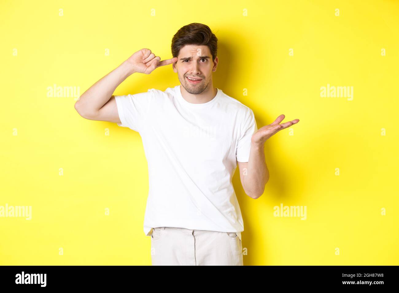 Confused and angry man pointing at head, scolding person for acting ...