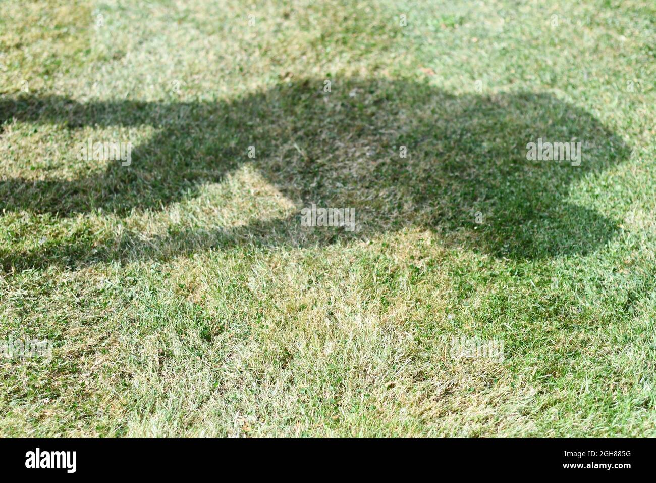 A man shadow on a summers day, whilst mowing the lawn in an English ...