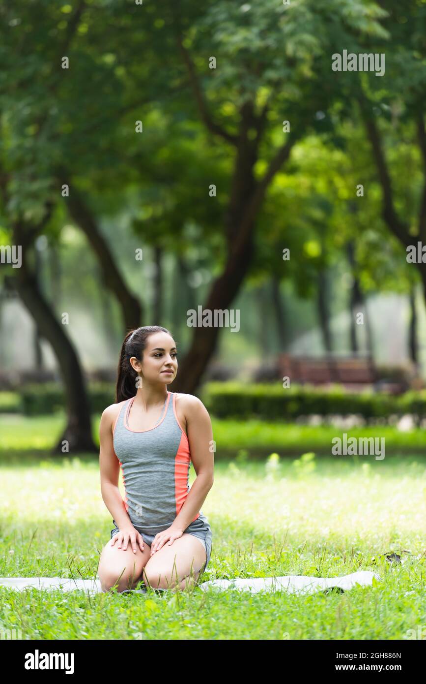 young fit woman sitting on toga mat in park Stock Photo - Alamy