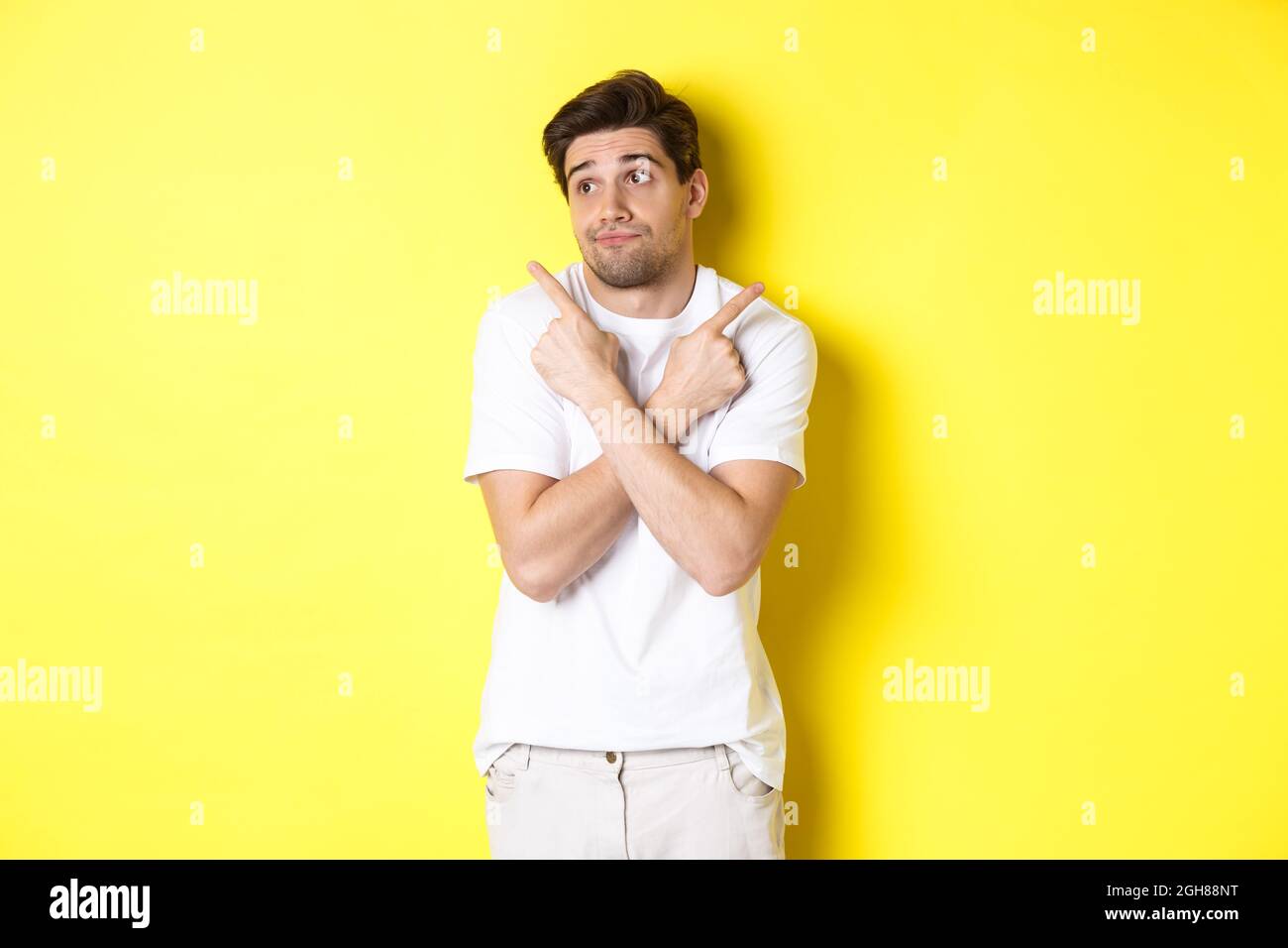 Indecisive man shrugging, pointing fingers sideways, troubled to choose ...