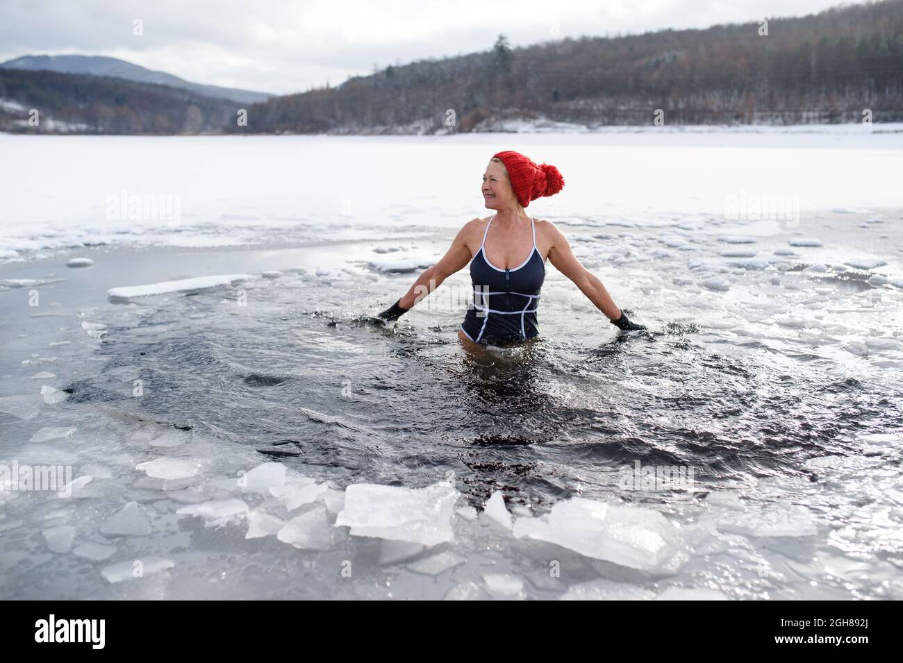 Front view of active senior woman in swimsuit outdoors in winter, cold ...