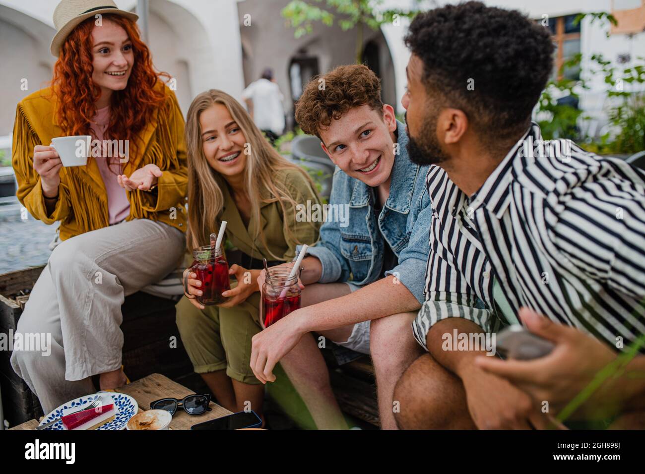 Group of happy young people sitting in outdoors cafe on town trip ...