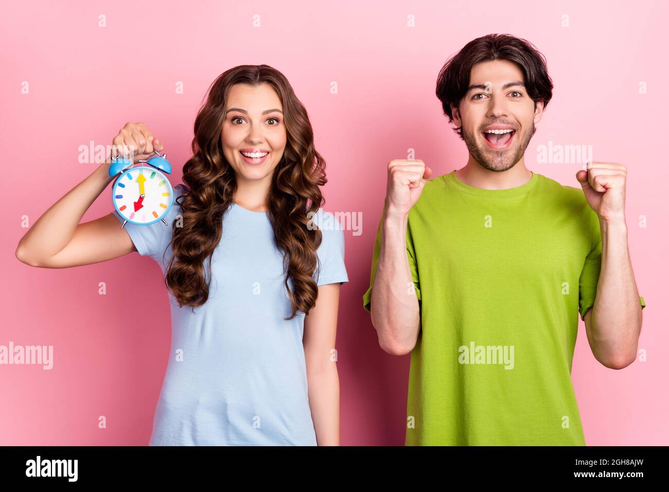 Photo of young happy couple hold hand clock alarm winner celebrate good ...