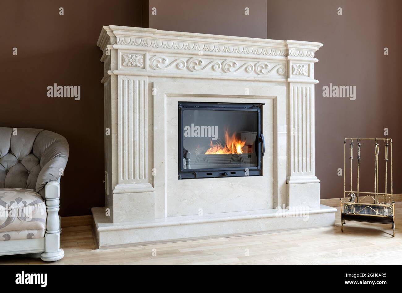 White marble fireplace in classic style with burning wood inside. Interior design concept Stock ...