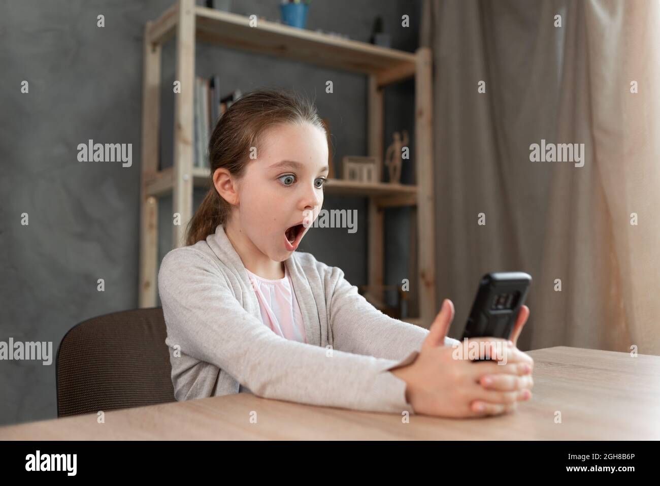 Close up portrait of anxious schoolgirl looking at the phone seeing bad ...