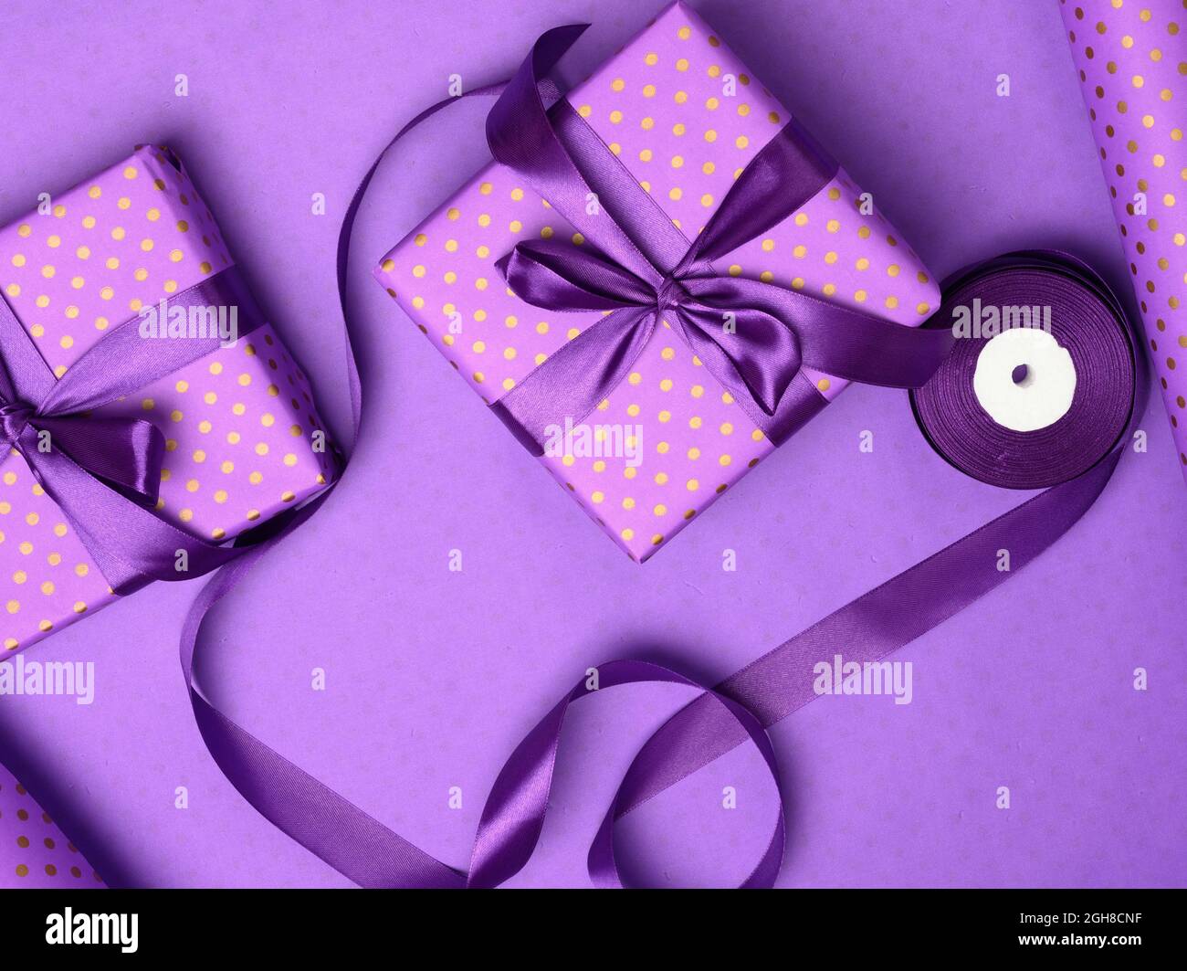 purple gift box wrapped in silk ribbon on a purple background, top view ...