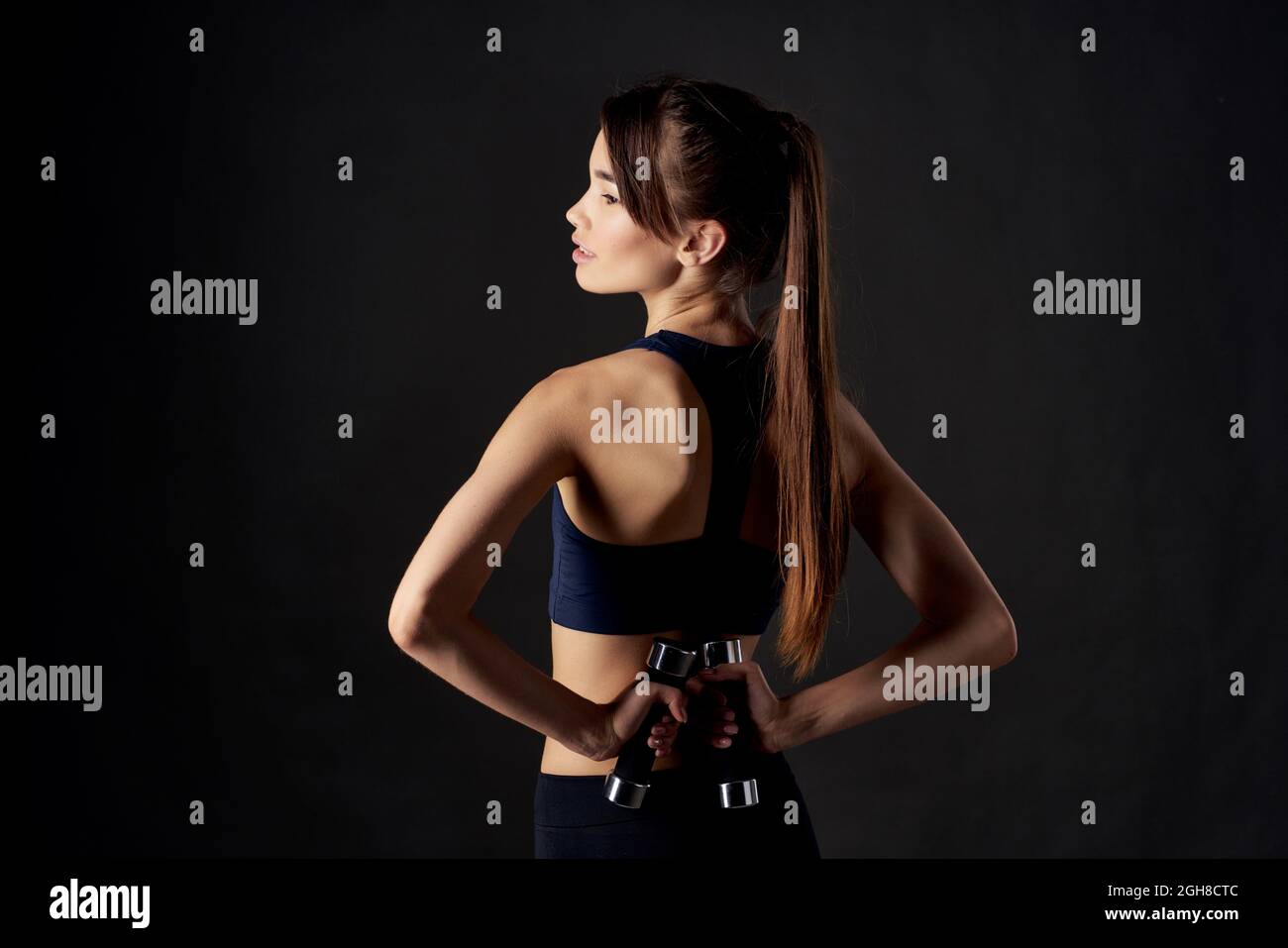 woman with dumbbells in hands dark background workout inflated muscles ...