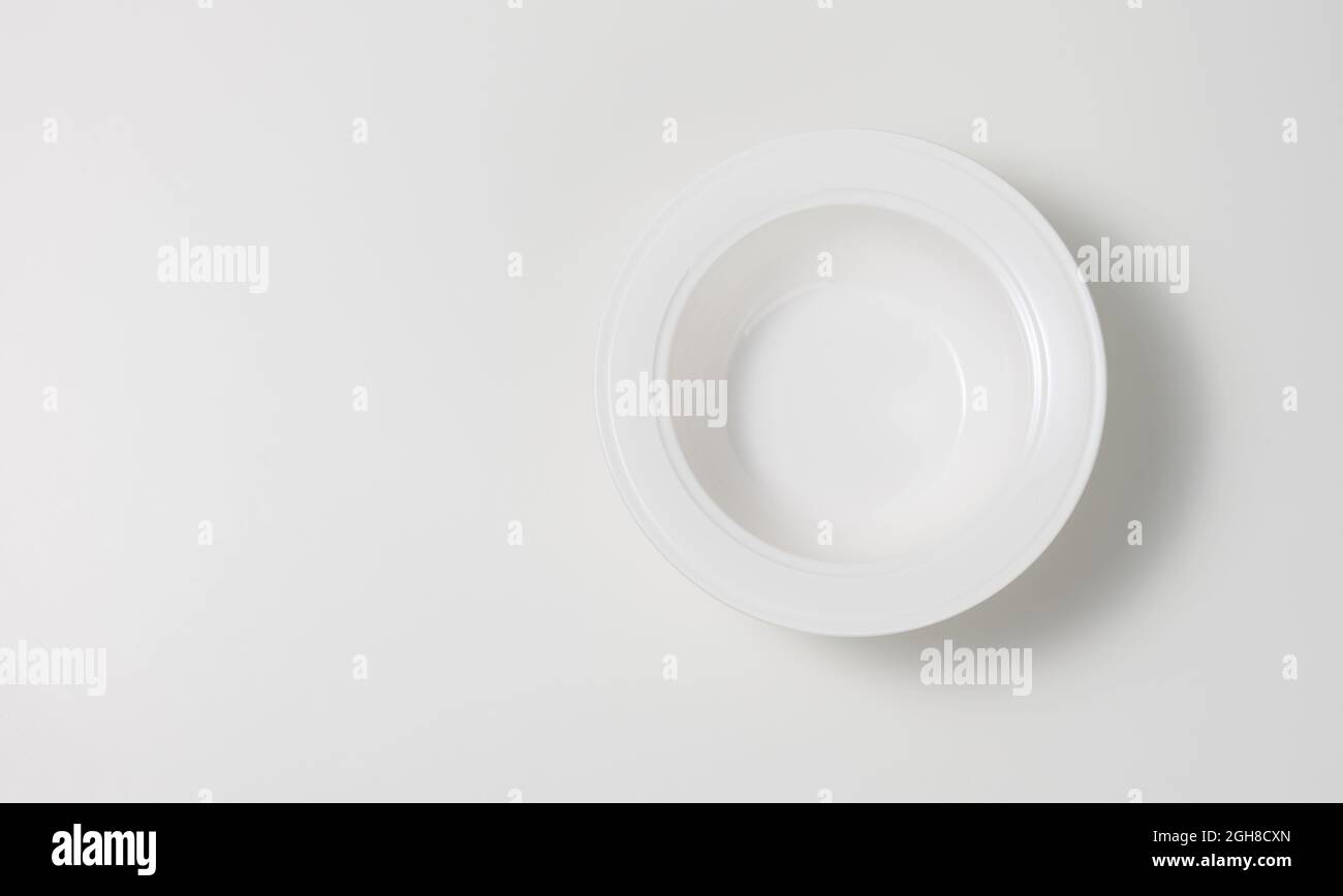 empty white round ceramic soup plate on white table, top view, copy ...