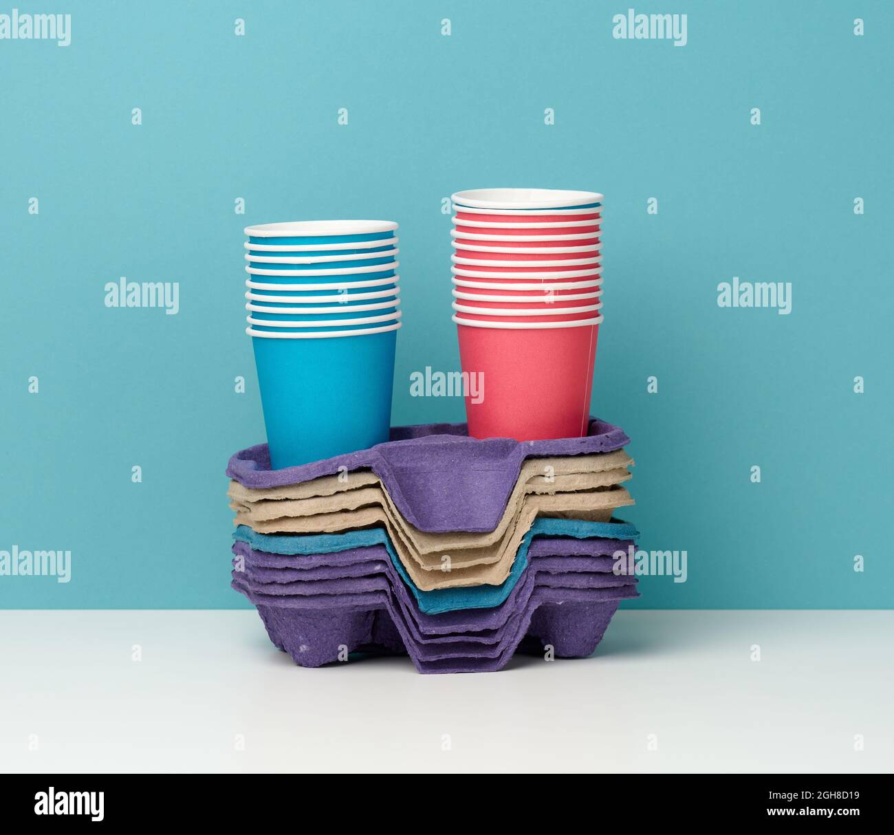 stack of paper disposable multi-colored cups and stand on white table ...