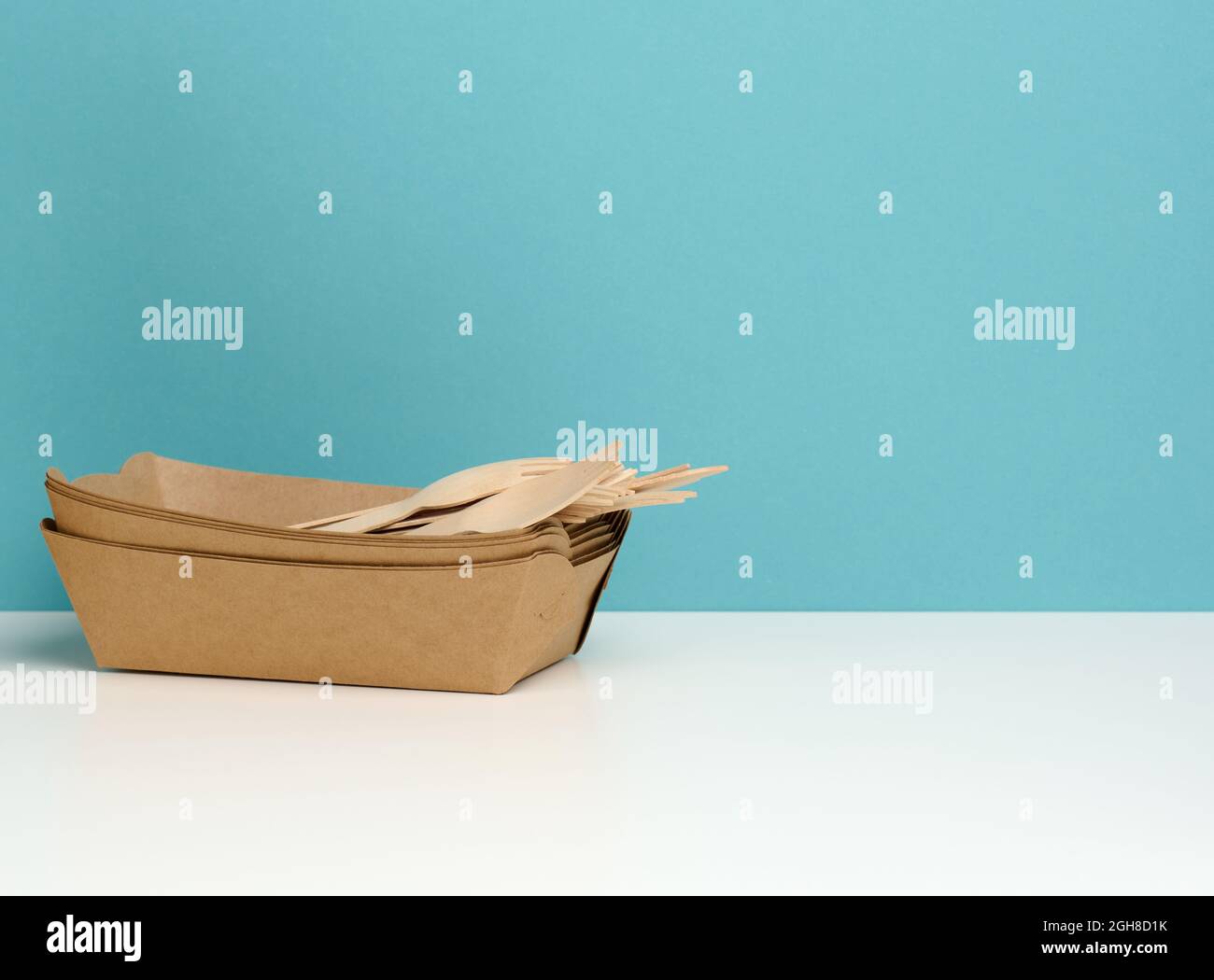 disposable paper rectangular plates, wooden forks and knives on white ...