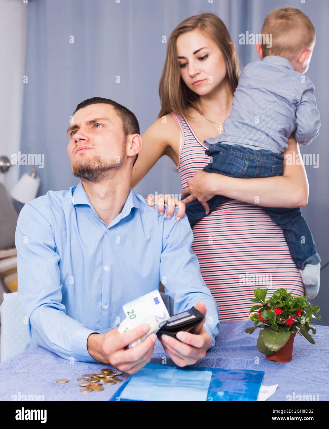 Portrait of grumpy wife asking money from husband siting a the table ...