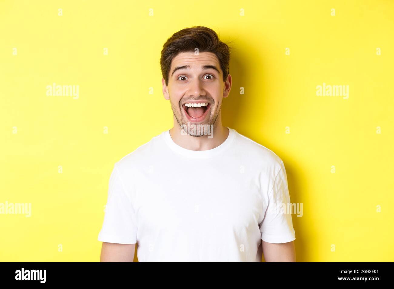 Close-up of surprised handsome guy reacting to great news, standing ...