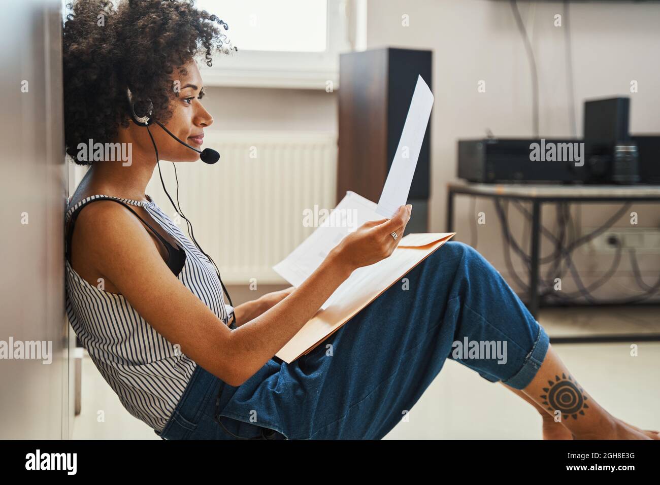 Focused lady in headphones with a microphone analyzing documentation ...