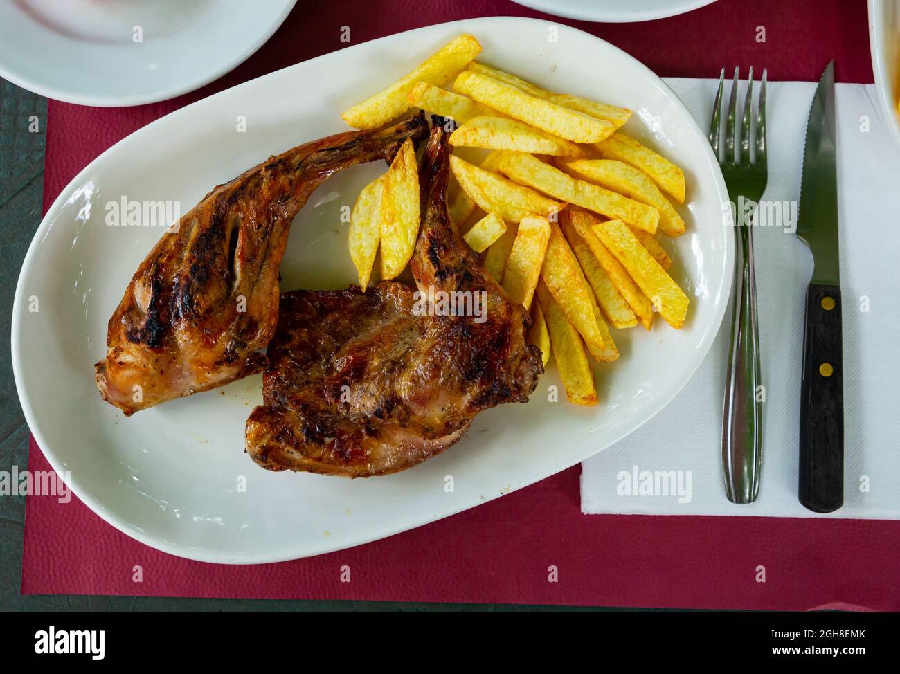 Grilled rabbit leg quarters served on white plate with crispy fried ...