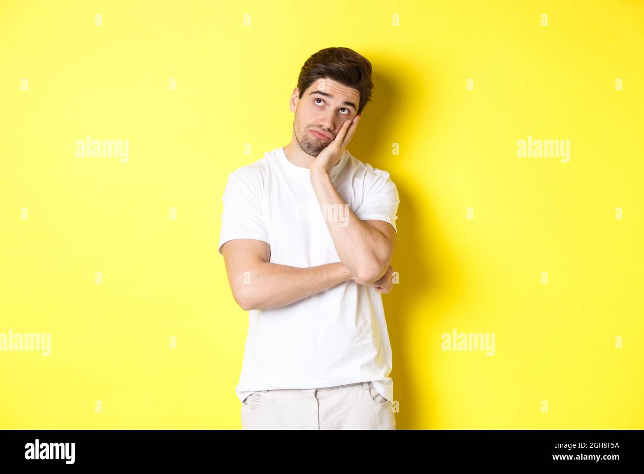 Bored and gloomy guy looking up, imaging things, standing over yellow ...