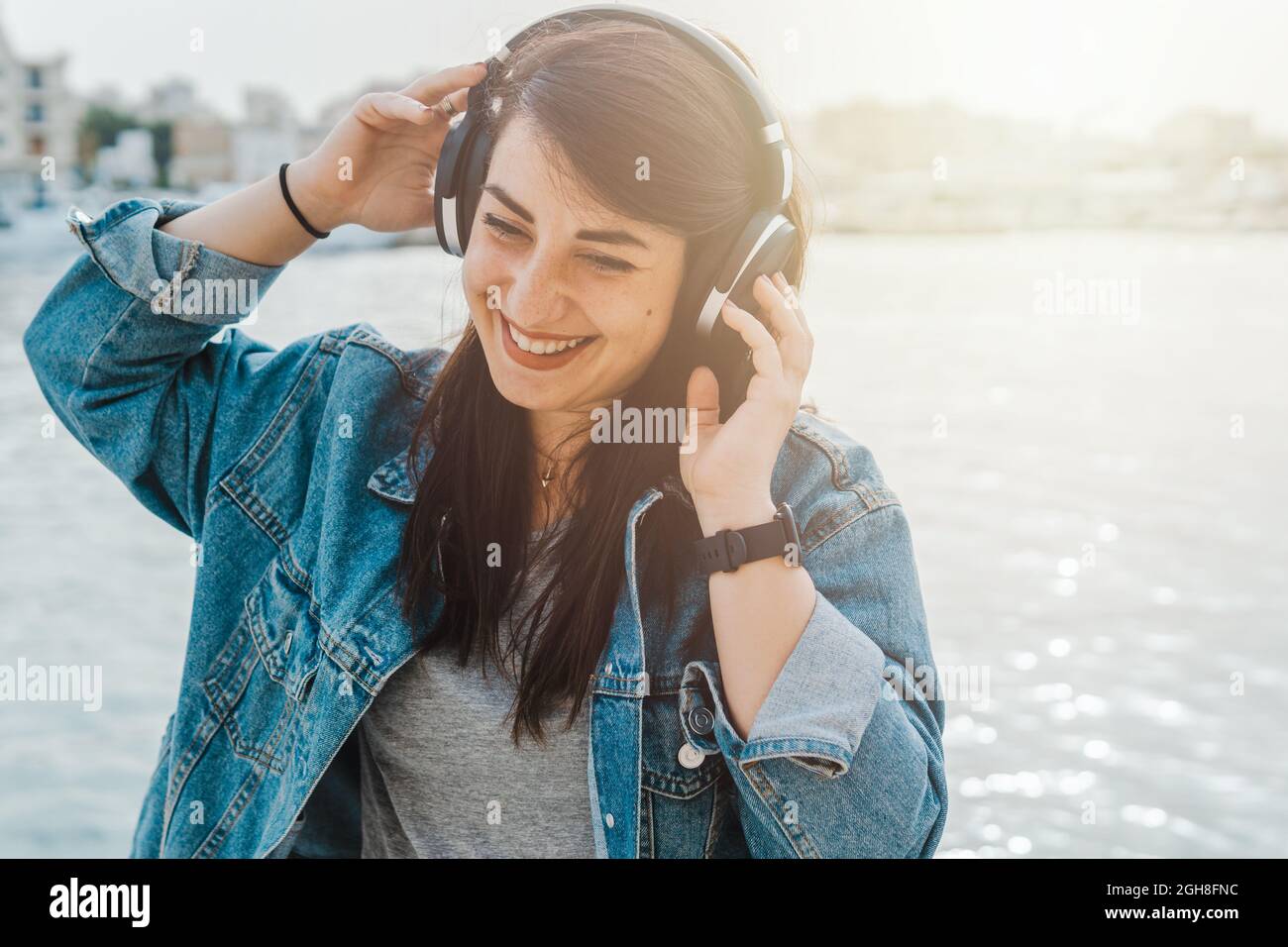 Young woman listens to music and podcasts with portable headphones ...