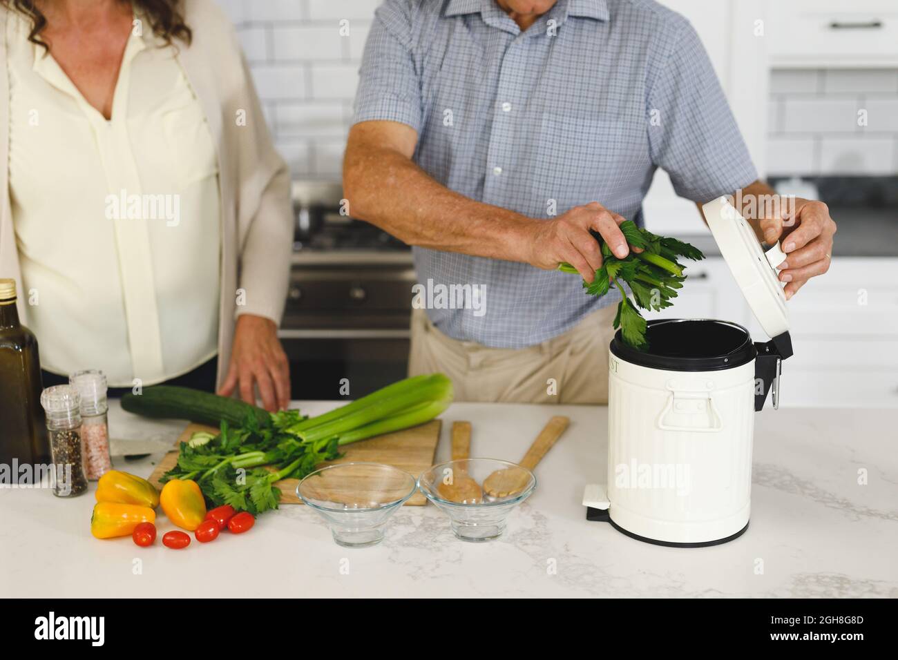 Midsection senior caucasian couple in modern kitchen, cooking together ...