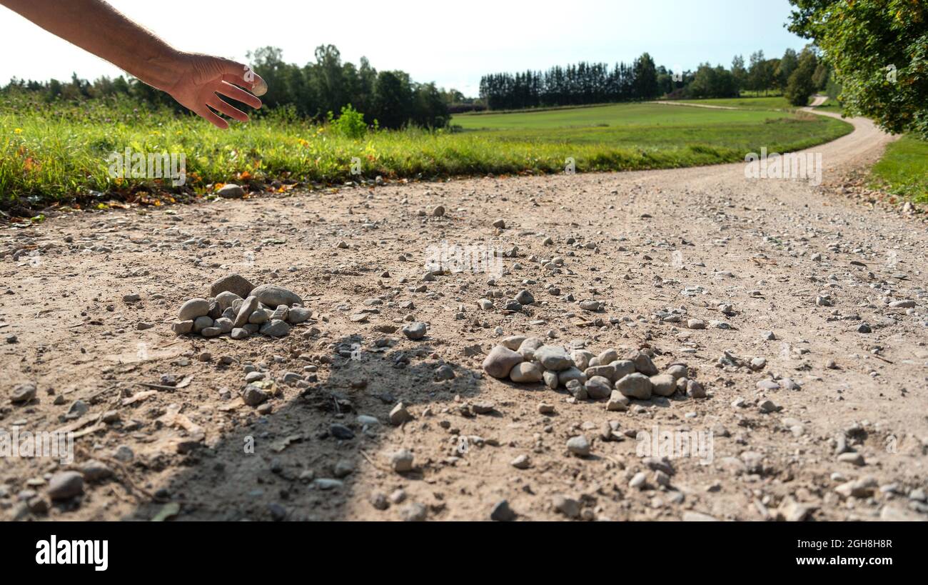 Hand with stone above the gravel road Stock Photo - Alamy