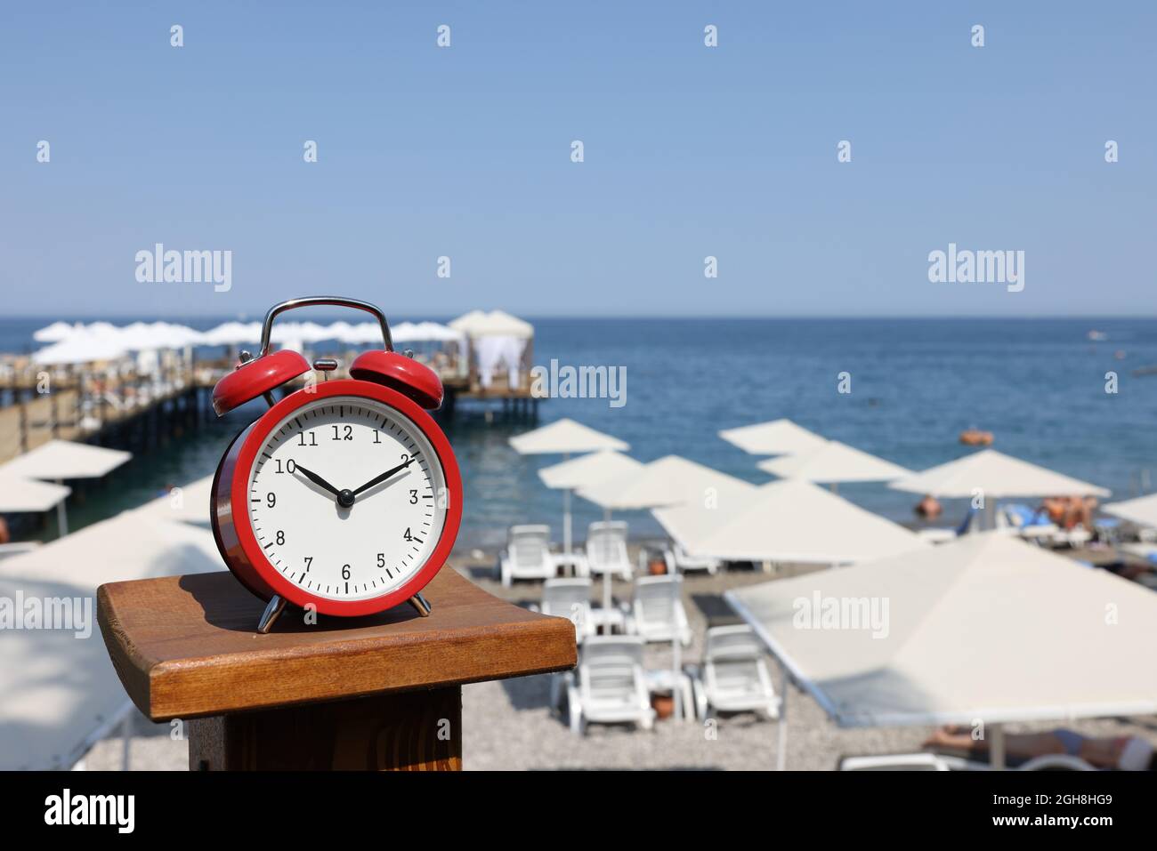 Red alarm clock stands against background of the beach and sea Stock ...