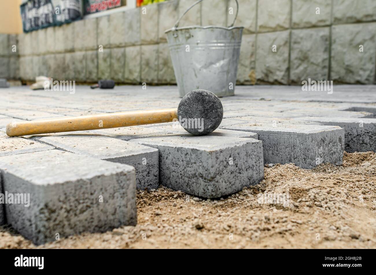 Rubber hammer on a gray pavement on the sand. Laying paving stones in ...