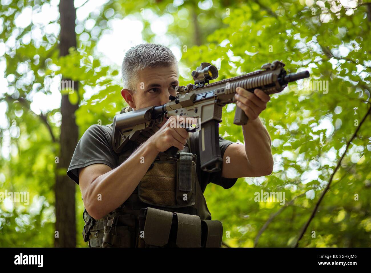A man standing with an airsoft assault rifle in military uniform in the ...
