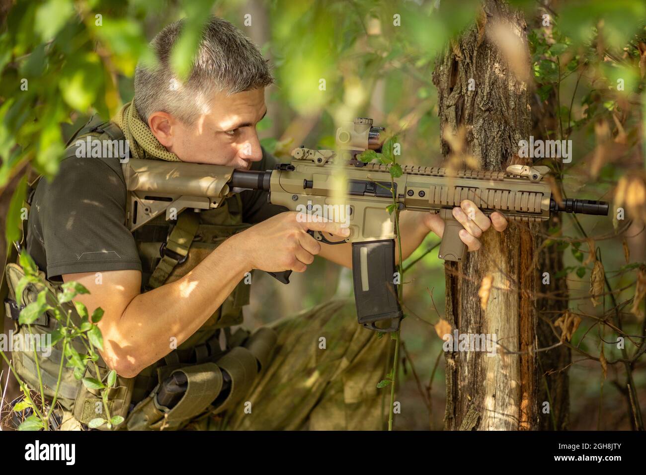 A man with an airsoft assault rifle in military uniform behind cover in ...